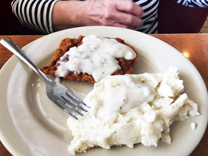 Country fried steak smothered in pepper gravy alongside cloud-like mashed potatoes—a plate that says "nap time" in the most delicious way possible.