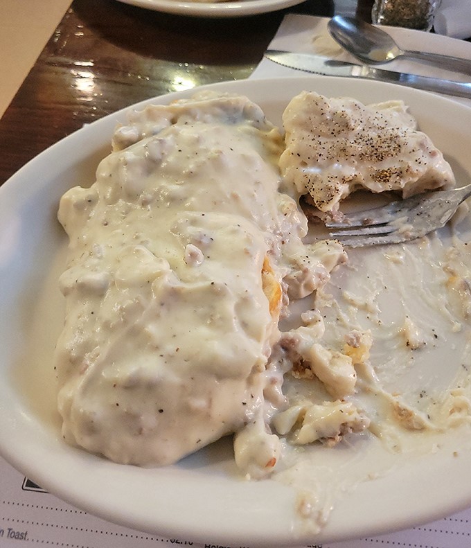 Biscuits drowning in creamy homestyle gravy – a Southern breakfast tradition that turns first-timers into lifetime devotees with just one forkful.