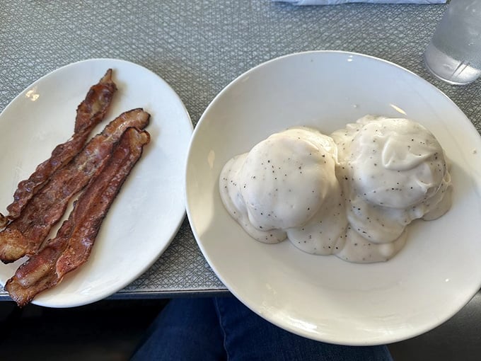 Southern comfort on two plates: crispy bacon strips alongside biscuits swimming in creamy pepper gravy. Some morning traditions are worth preserving forever.