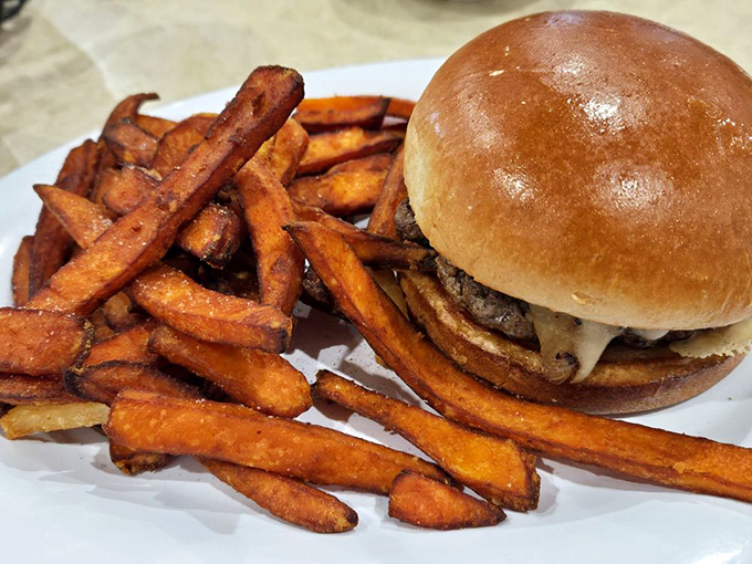 A burger that requires both hands and a strategy, paired with sweet potato fries that could make a Frenchman weep with envy.