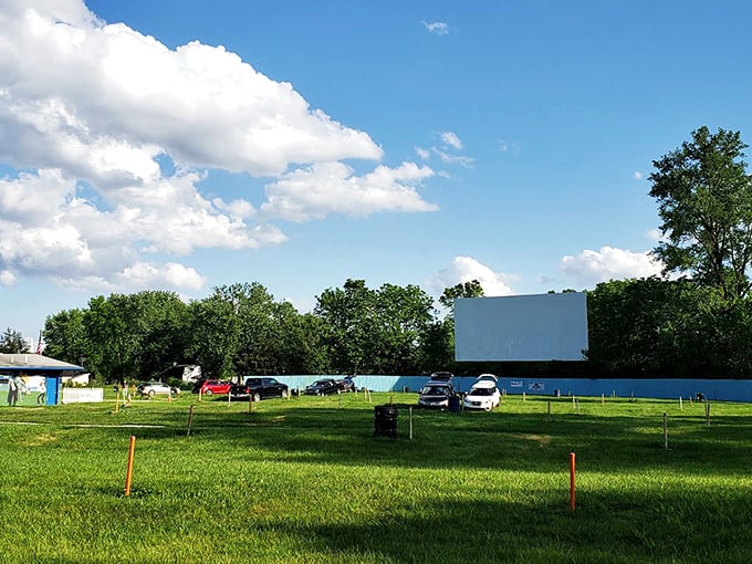The big screen waits patiently amid blue skies and green grass, a canvas ready to paint stories across the twilight.