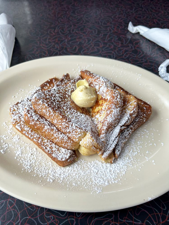 French toast that's dressed for success with powdered sugar snow and butter melting like sunshine on a perfect morning.