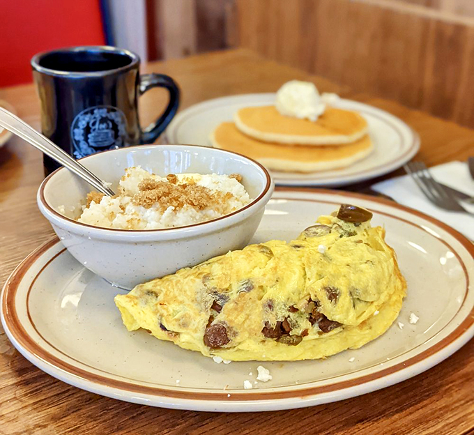 A masterclass in breakfast architecture: fluffy omelet loaded with fillings alongside creamy grits that would make any Southerner nod in approval.