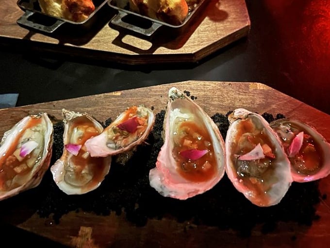 Ocean treasures on display like precious artifacts &ndash; these oysters are dressed to kill with vibrant garnishes on a bed of darkness. 