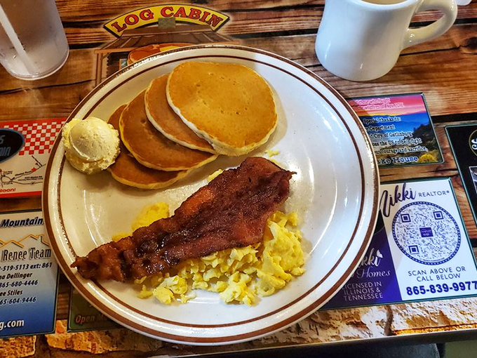 The holy trinity of breakfast: perfectly golden pancakes, fluffy scrambled eggs, and bacon that's achieved crispy-yet-tender perfection.