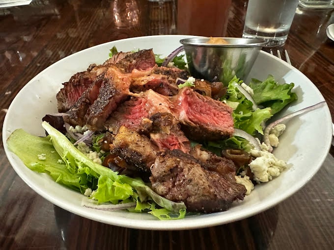 The kind of perfectly seared steak that makes you momentarily forget your table manners. Notice how it rests atop those green beans like it knows it's the star of the show.