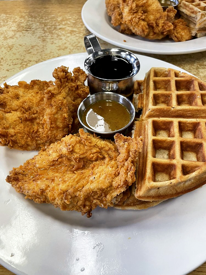 The waffle-to-chicken ratio here is mathematical perfection, with those metal cups of syrup and sauce standing by like flavor bodyguards.