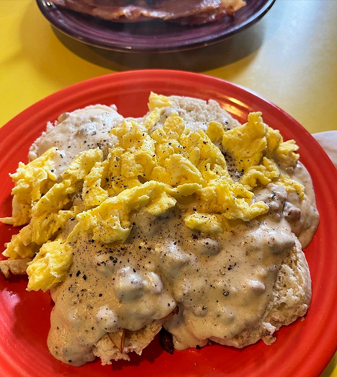 The holy trinity of breakfast comfort: perfectly toasted raisin bread, farm-fresh eggs, and a blanket of peppery sausage gravy that could make a grown person weep with joy.