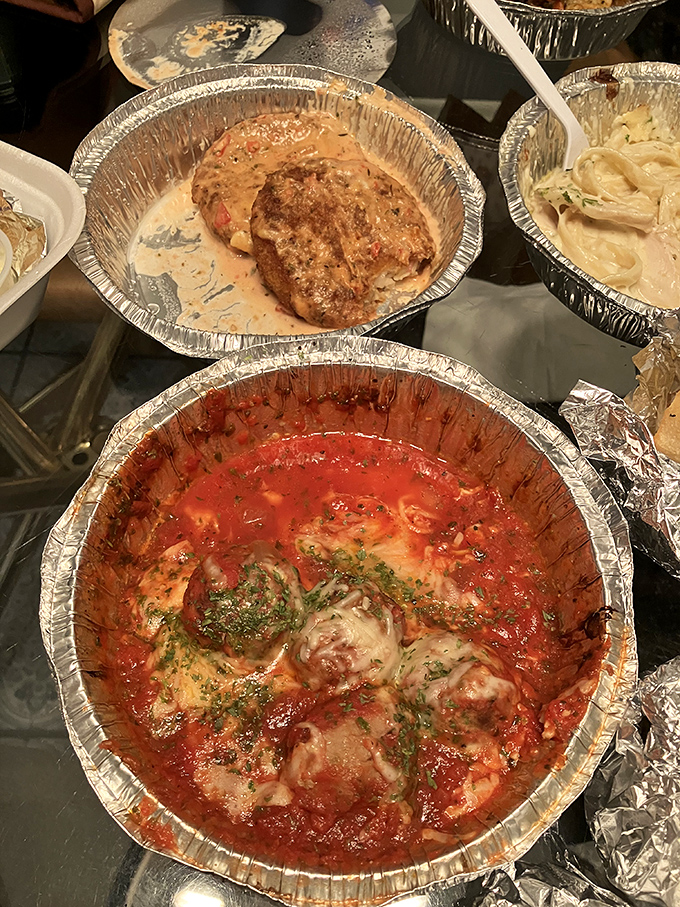 The holy trinity of comfort: meatballs swimming in marinara, pasta bathed in cream sauce, and that golden-brown crab cake stealing the spotlight.