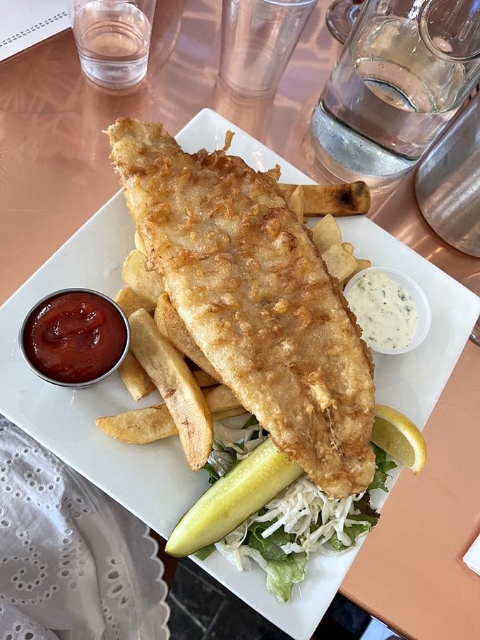 Proper fish and chips done right—flaky white fish in crispy batter alongside chunky chips, with essential accompaniments of lemon and tartar sauce.