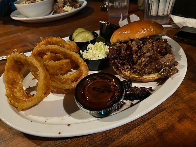 The pulled pork sandwich arrives with crispy onion rings that could double as edible jewelry. That slaw adds the perfect cool crunch to each bite.