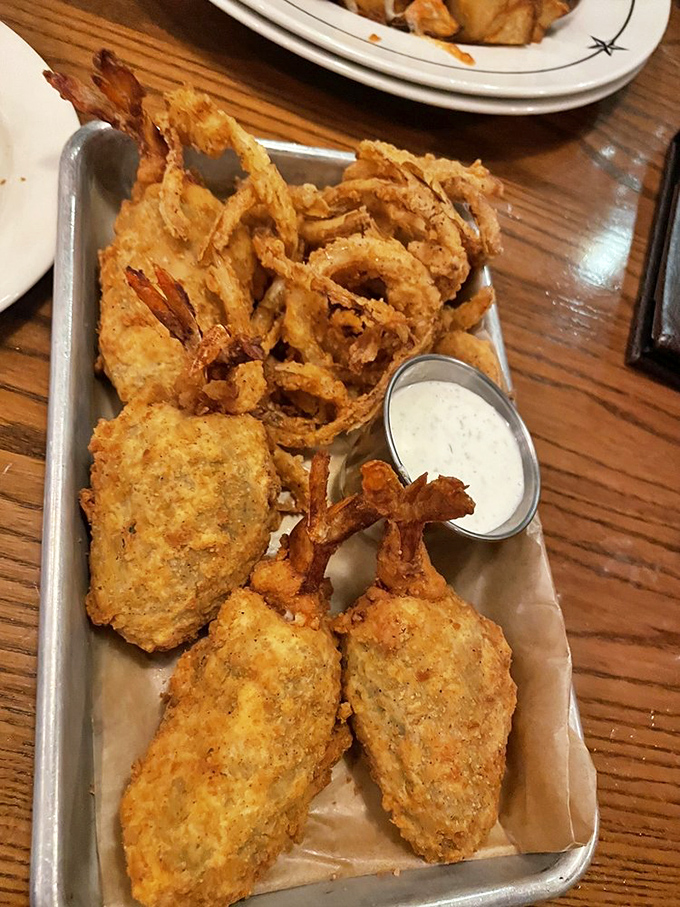 Fried perfection on a metal tray&mdash;where crispy batter meets tender chicken and onion rings. The dipping sauce is just showing off at this point.