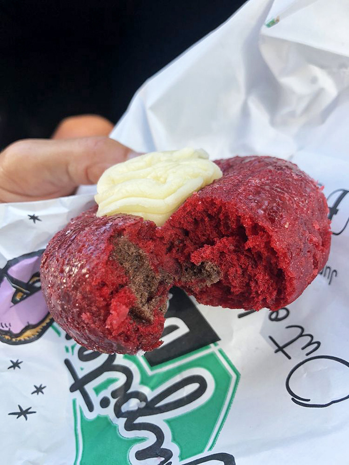 The red velvet donut, dramatically split to reveal its chocolate soul. Breakfast theater at its most delicious.