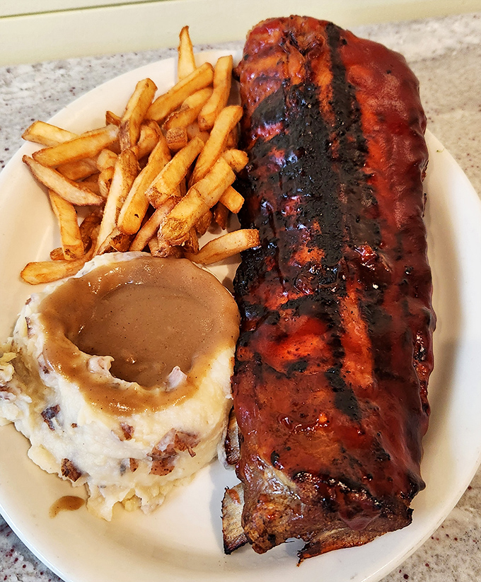 The holy trinity of comfort: smoky ribs, golden fries, and mashed potatoes with gravy deep enough to dive into.