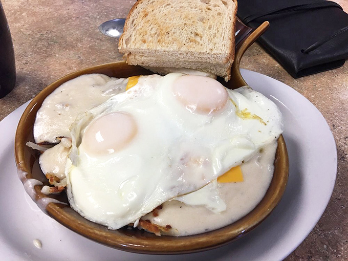 Two sunny-side up eggs rest atop what appears to be hash browns&mdash;a simple pleasure that somehow tastes better when someone else makes it.