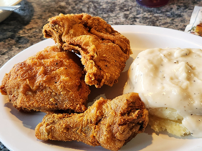 The holy trinity of comfort: perfectly fried chicken, creamy mashed potatoes, and gravy that could make a vegetarian reconsider their life choices.
