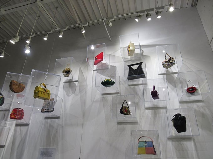 Handbags float like colorful butterflies in this artistic display, each telling its own story across the decades.