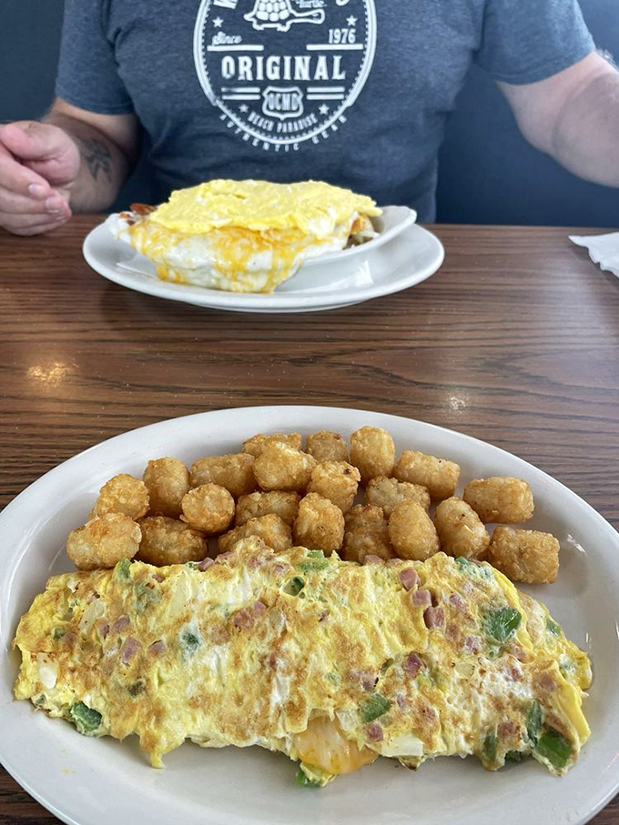 An omelet that's having an identity crisis as a work of art, paired with golden tater tots that could make a potato proud.