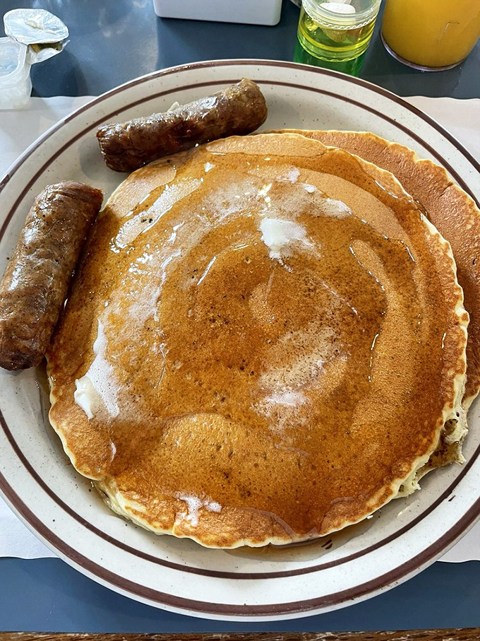 Pancakes the size of vinyl records, golden-brown and waiting for their maple syrup bath. Sausage links standing guard like delicious sentries.