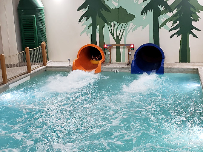 Orange and blue water slides emptying into a splash pool &ndash; like colorful straws delivering pure joy directly to your vacation experience.