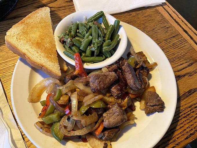 Simple pleasures done right: tender beef tips with peppers and onions alongside vibrant green beans. Proof that straightforward food executed perfectly beats fancy any day of the week.