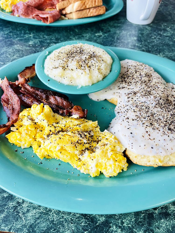 Southern breakfast perfection: creamy grits, crispy bacon, fluffy eggs, and gravy-smothered biscuits. Diet plans surrender immediately upon sight.