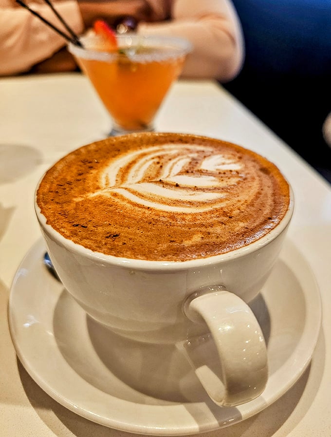 Latte art so pretty you almost don't want to drink it. Almost. The cocktail lurking in the background suggests serious brunch commitment.