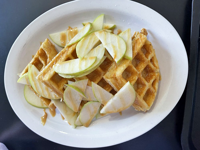 Fresh apple slices dance across a golden waffle canvas—proof that sometimes the best art galleries are actually on your breakfast plate.