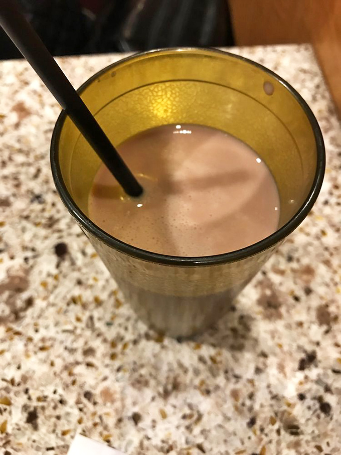 Chocolate milk in a golden chalice&mdash;because after conquering the buffet battlefield, every hero deserves a proper victory toast.