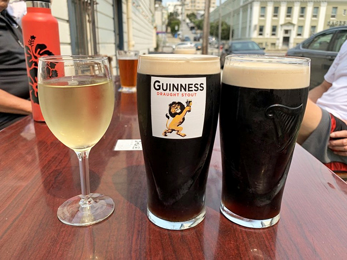 Three glasses that tell different stories: wine for sophistication, Guinness for tradition, and another Guinness because one is never enough.