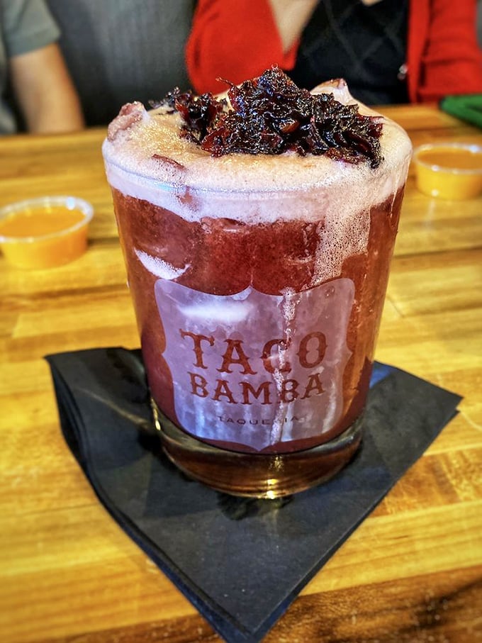 This isn't just a margarita—it's a sunset in a glass, topped with what appears to be hibiscus-tamarind goodness that would make your regular happy hour weep.