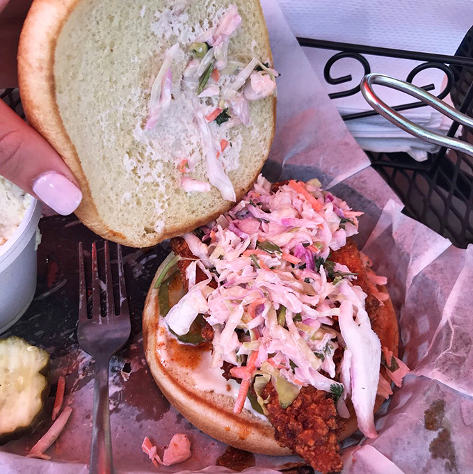 This isn't just a sandwich; it's architecture. Pink slaw provides cooling relief from the crimson-hued chicken's fiery embrace.