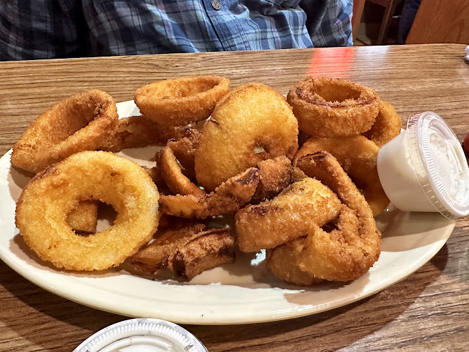 Onion rings stacked like delicious golden halos – crispy, light, and the perfect companion for dipping into that side of ranch.