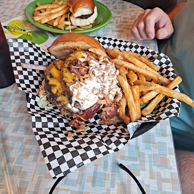 Behold: a burger that requires jaw exercises before attempting. Melted cheese cascades like a yellow waterfall over bacon and beef in this masterpiece of American engineering.