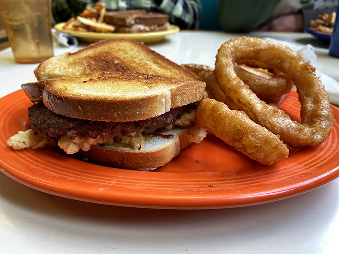 This isn't just a sandwich; it's a masterclass in burger architecture with golden onion rings standing guard.