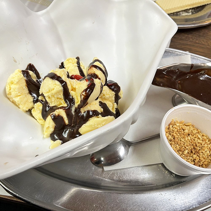 Hot fudge cascading over vanilla ice cream like chocolate lava meeting snow-capped mountains - a geological wonder you can eat.