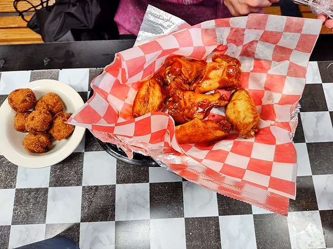 These wings, glistening with sauce and nestled in their red-checkered paper bed, are what happens when chicken fulfills its highest purpose.