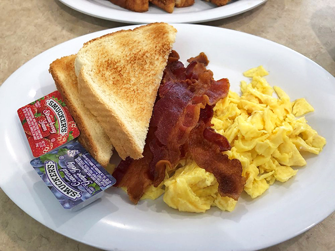 The holy trinity of breakfast: golden toast, bacon cooked to that perfect crisp-yet-chewy state, and eggs that beam sunshine from the plate.