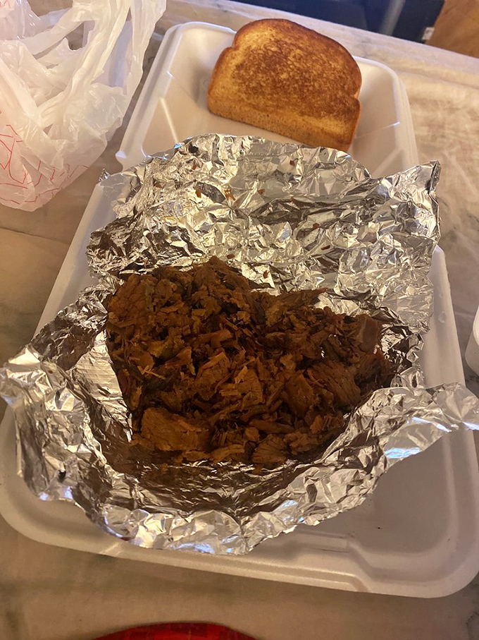 Foil-wrapped brisket with Texas-worthy bark and a slice of toast that's about to embark on a sauce-soaking mission.