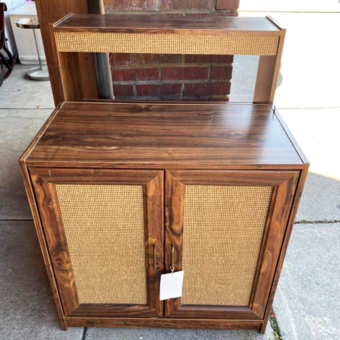 This cane-front cabinet whispering tales of mid-century parties would be the conversation piece your living room never knew it needed.