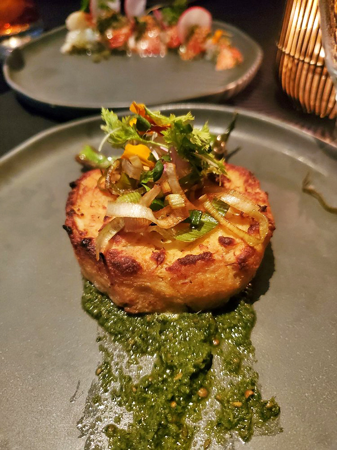 This isn't just a crab cake; it's a savory disc of seafood joy, perched on vibrant green sauce like it's showing off.