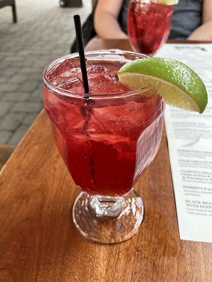 A ruby-red beverage that whispers "vacation" with every sip, garnished with lime and served in a glass that means business.