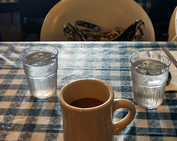 Coffee in a sturdy mug on a blue checkered tablecloth &ndash; sometimes the simplest pleasures are the ones that feel most like coming home.