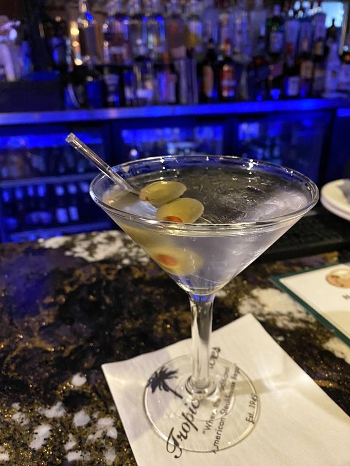 A classic martini with olives stands ready for sipping—this isn't just a cocktail, it's liquid sophistication in stemware.