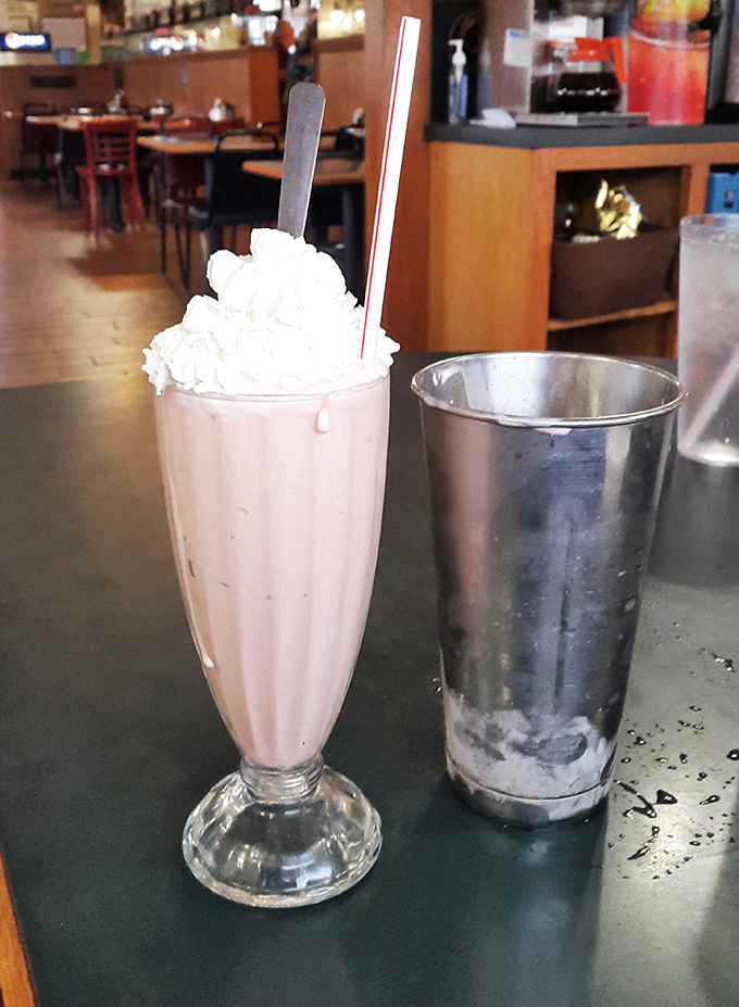 This isn't just a milkshake &ndash; it's a frothy pink skyscraper of nostalgia topped with a cloud of whipped cream that demands both a straw and spoon.