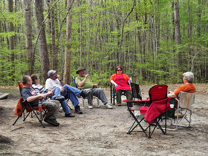 Camping chairs form a woodland living room, where conversation flows as freely as the nearby creek.
