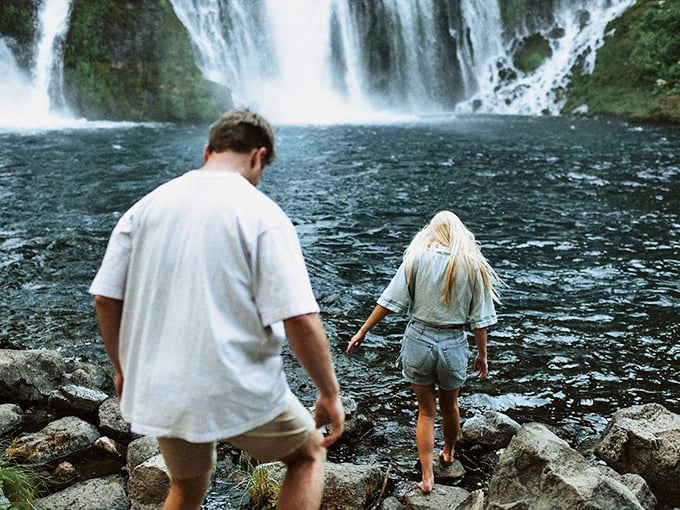 Explorers navigating the rocky shoreline, drawn like moths to the misty magnetism of California's liquid masterpiece.