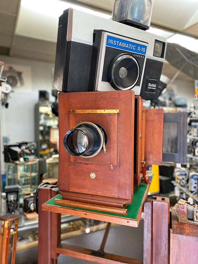 The iconic Kodak Instamatic X-15 sits atop its wooden ancestor, spanning a century of innovation in a single frame. From bellows to buttons!
