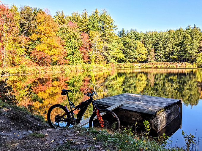 Fall's fiery palette transforms Mount Holyoke's waters into a kaleidoscope of color, with a rustic dock inviting quiet contemplation.