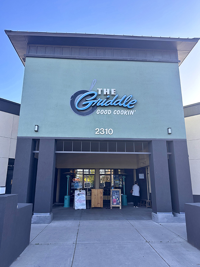The Griddle's entrance beckons like a portal to breakfast paradise. That blue awning might as well be a superhero cape for morning hunger rescue.